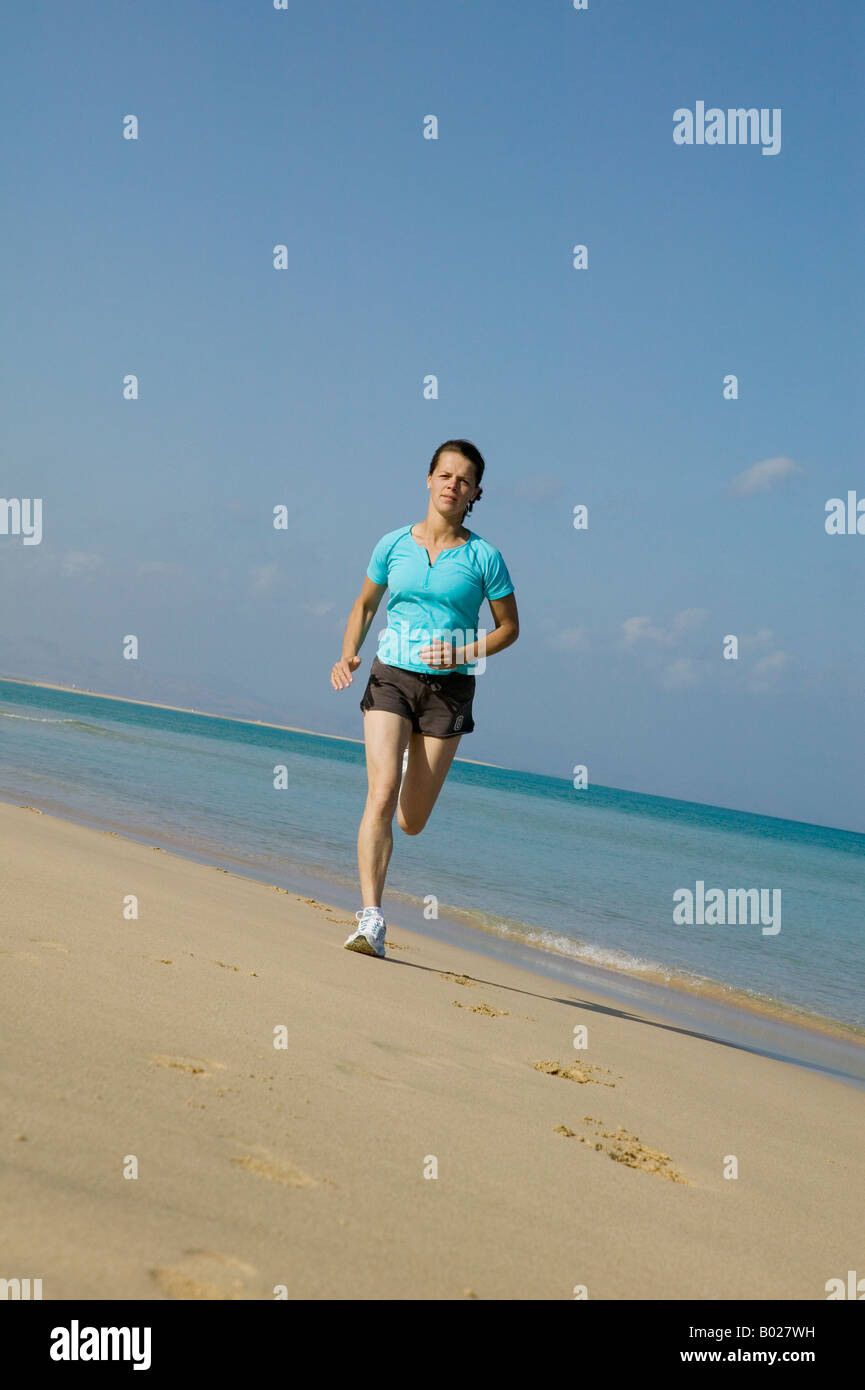 full body portrait of young woman jogging on beach Stock Photo - Alamy