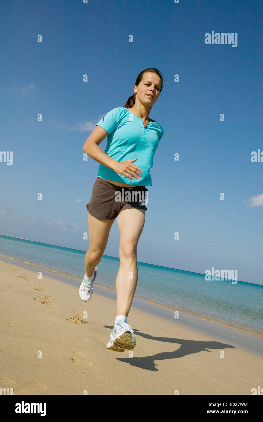 full body portrait of young woman jogging on beach Stock Photo - Alamy