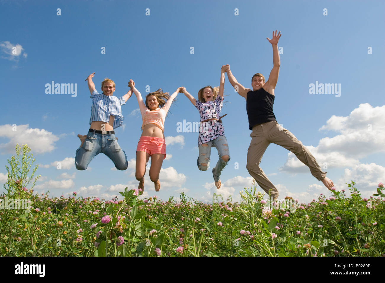 group of four friends jumping in summer meadow Stock Photo - Alamy