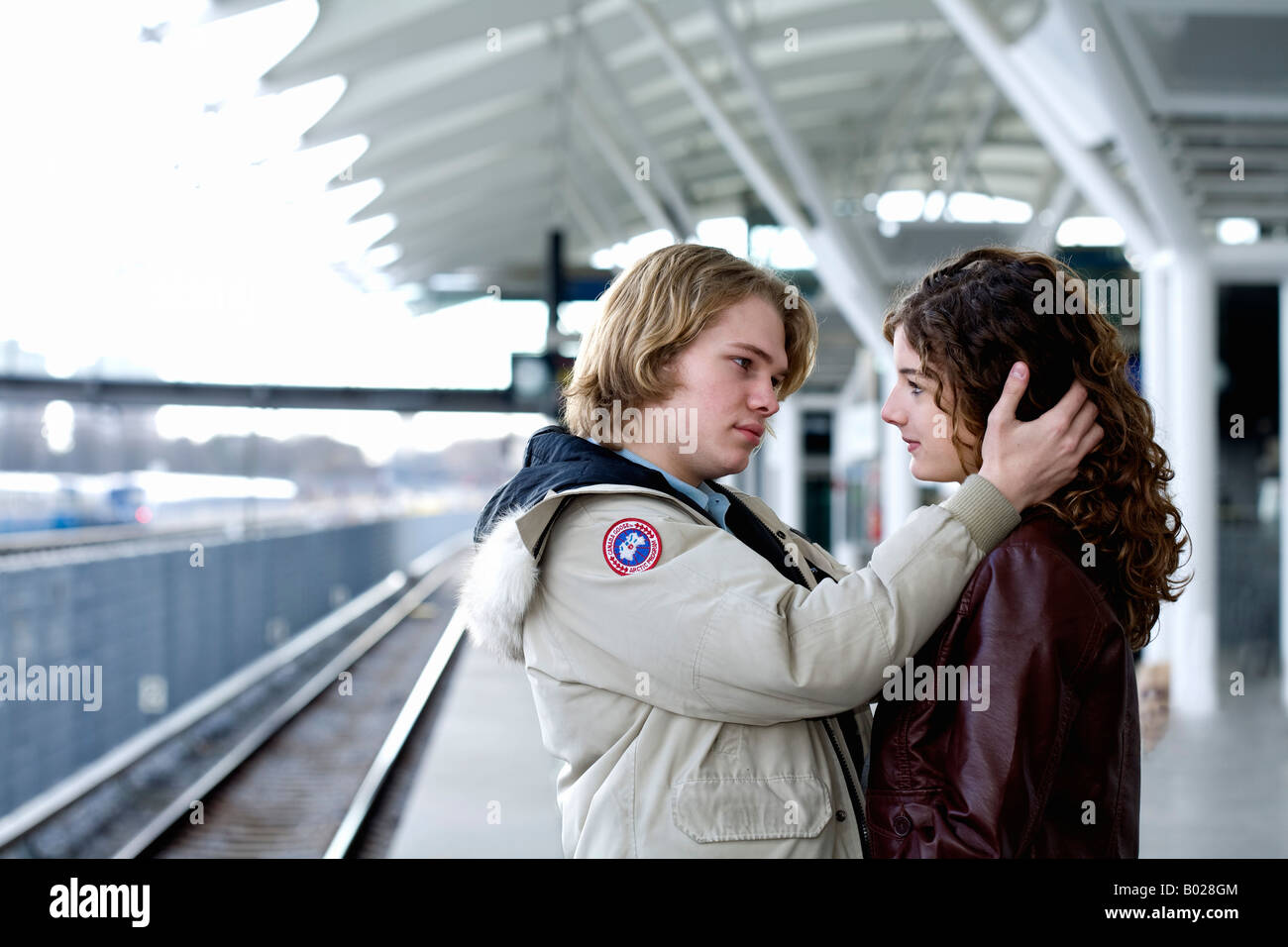 sad teenage couple embracing at station Stock Photo - Alamy