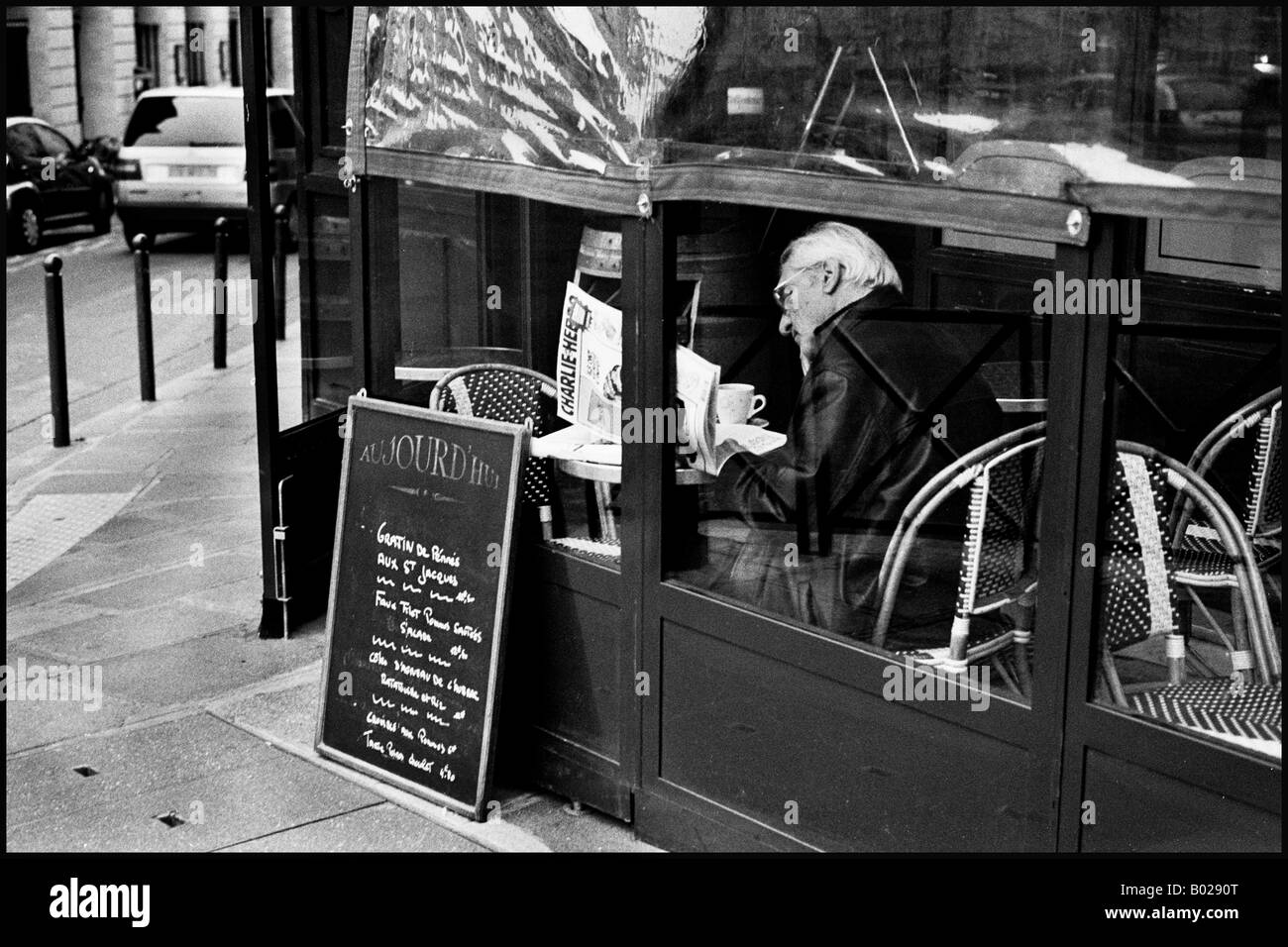 Man reading newspaper in a cafe in Paris Stock Photo - Alamy