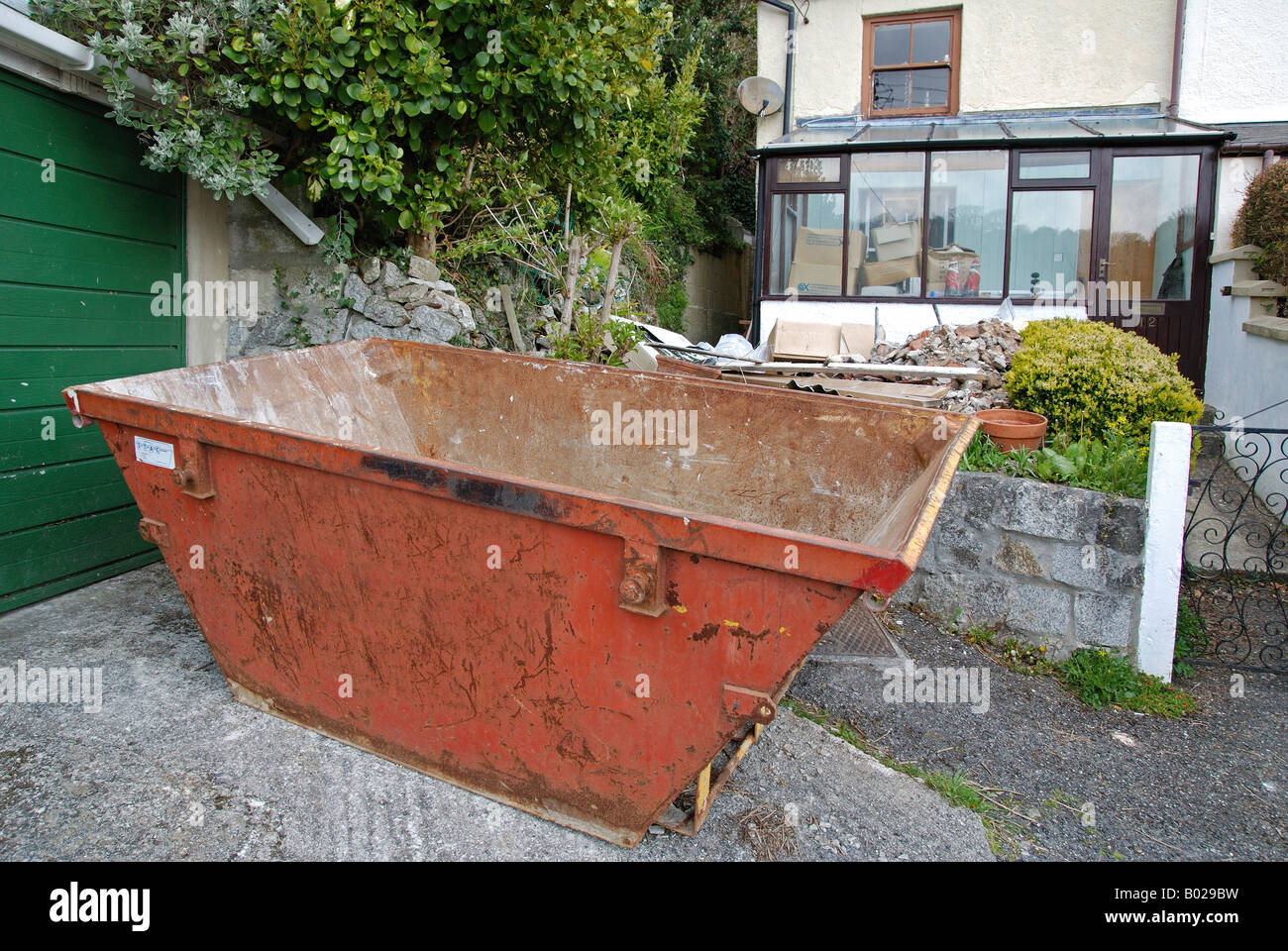 an empty skip outside of an old cottage that is being renovated in ...