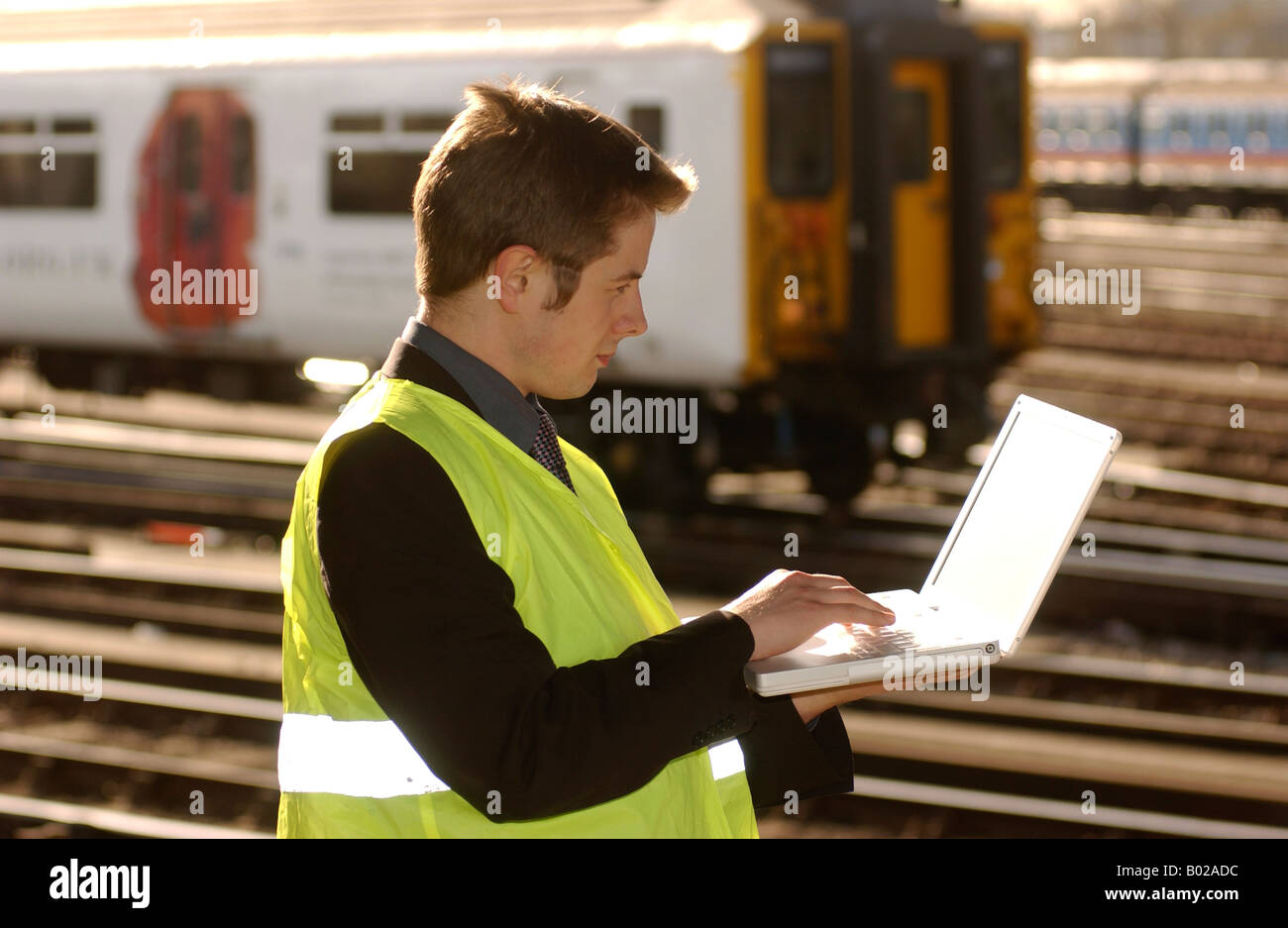 Man on railway platform using laptop computer Stock Photo - Alamy