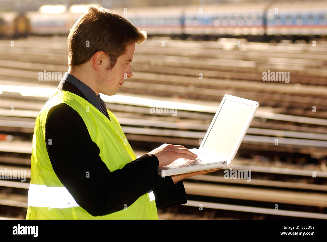 Man on railway platform using laptop computer Stock Photo - Alamy