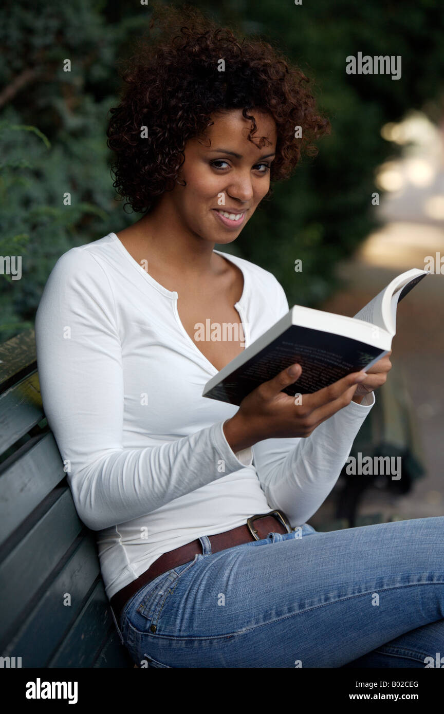 Girl reading a book on a park bench, ethnic background of model half ...
