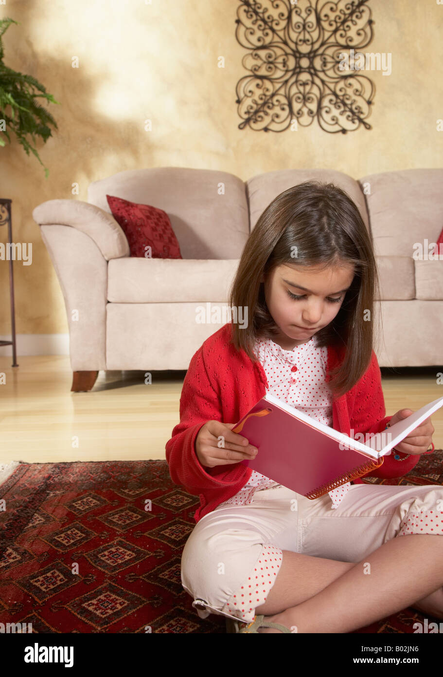 Middle Eastern girl reading on floor Stock Photo - Alamy