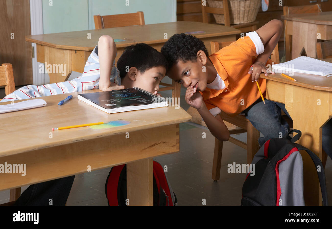 Multi-ethnic boys whispering in class Stock Photo - Alamy