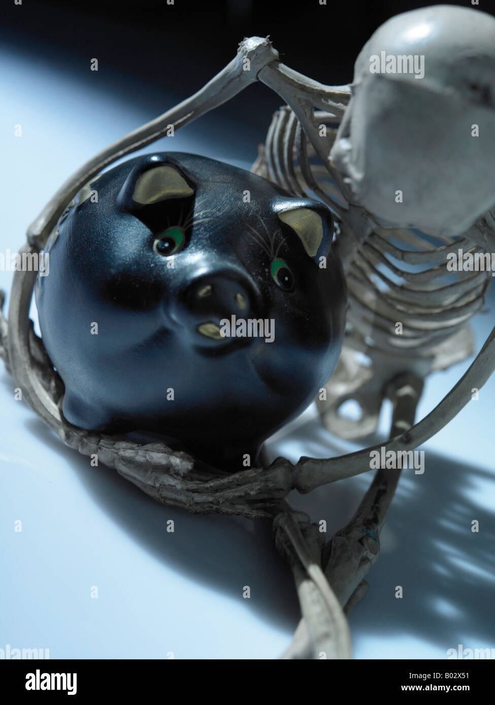 Front view of skeleton grabbing piggy bank Stock Photo - Alamy