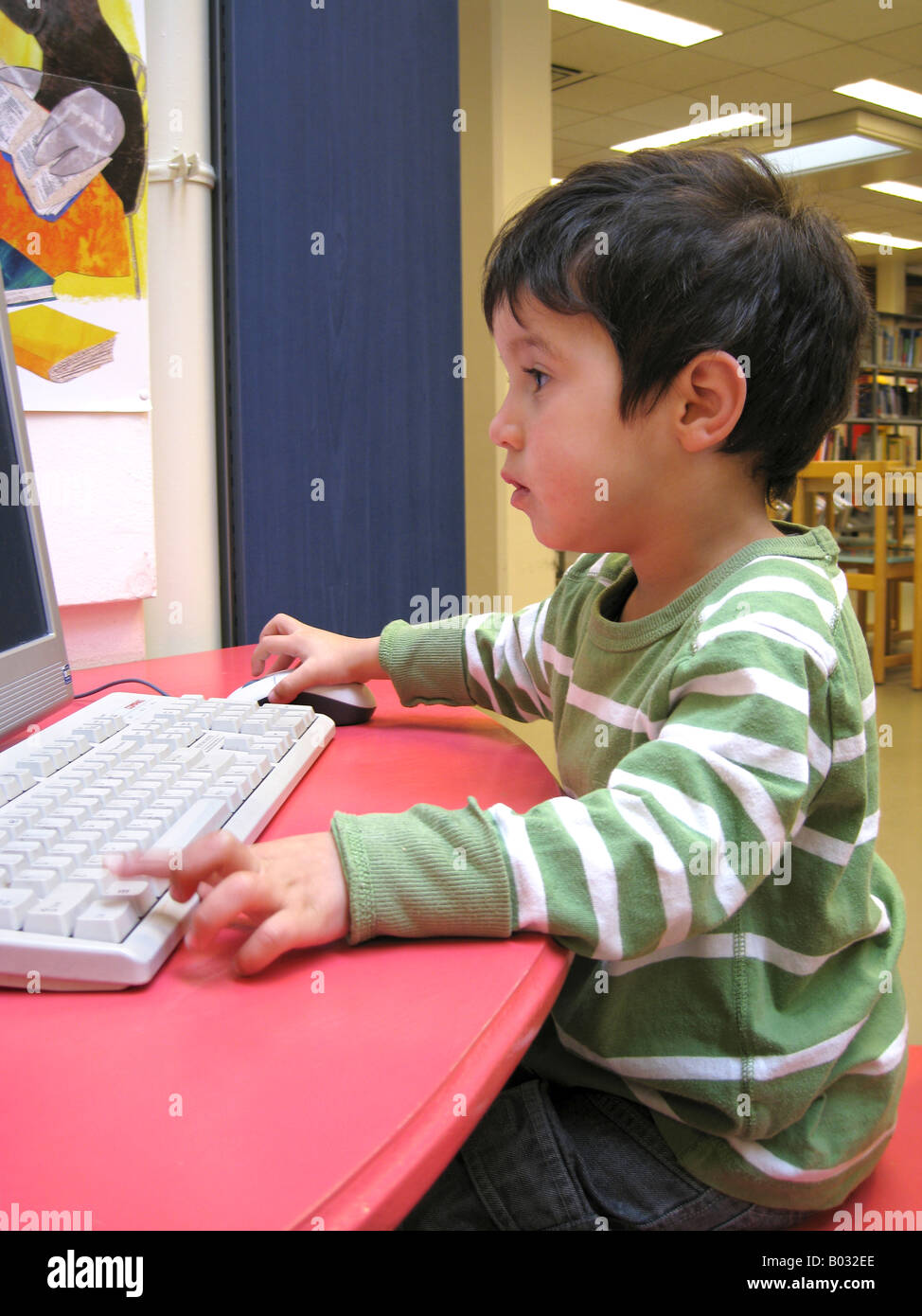 Little boy behind a computer in the library Stock Photo - Alamy