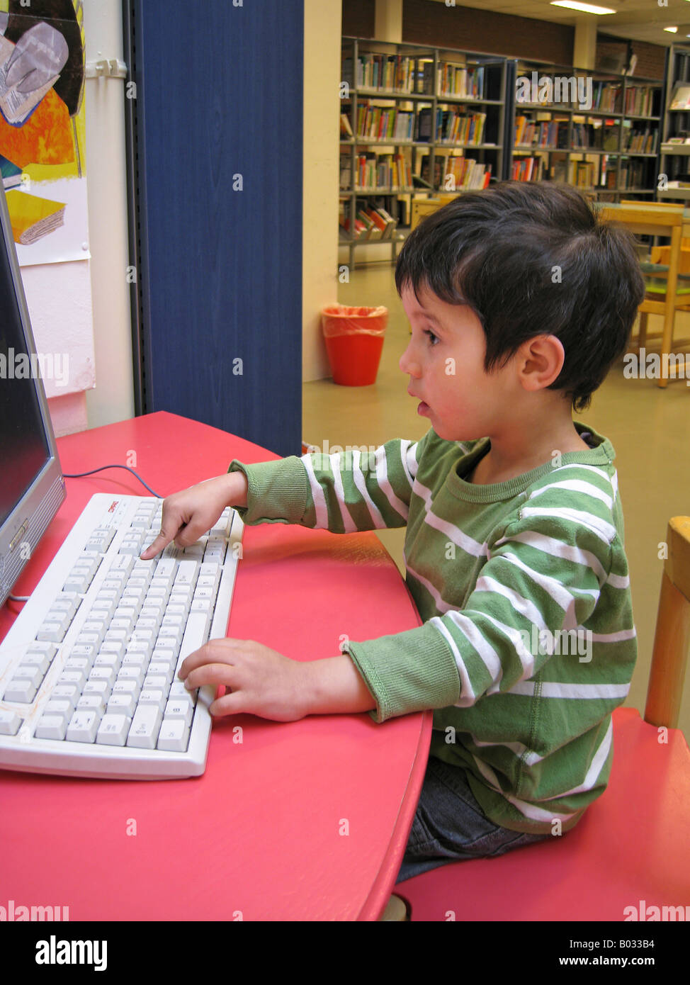 Little boy behind a computer in the library Stock Photo - Alamy