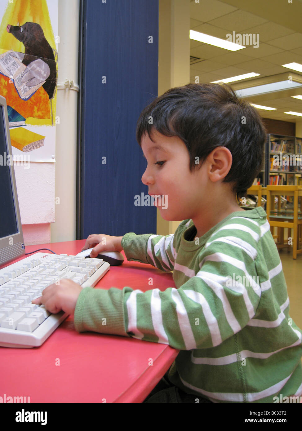 Little boy behind a computer in the library Stock Photo - Alamy