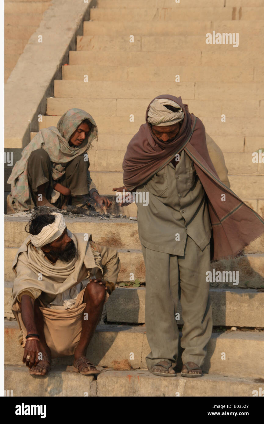 2 Indian men talking while a third tends a fire on the Ghats in ...