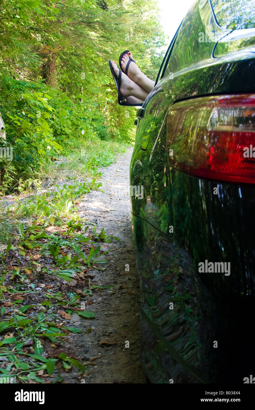 A young woman sleeps in the car with her feet dangling out Stock Photo ...