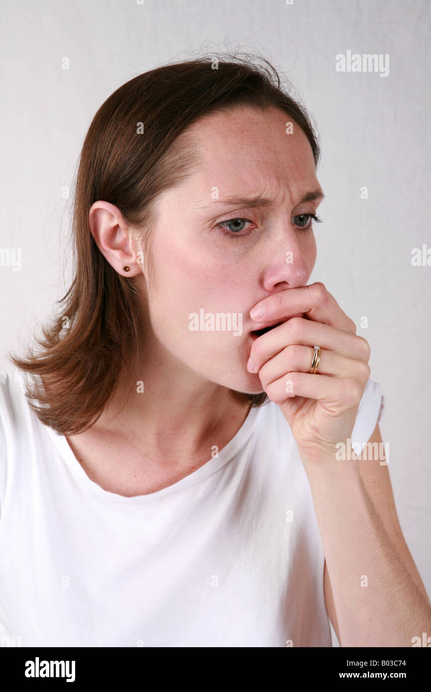 Young woman politely covers mouth with hand and fingers while coughing ...