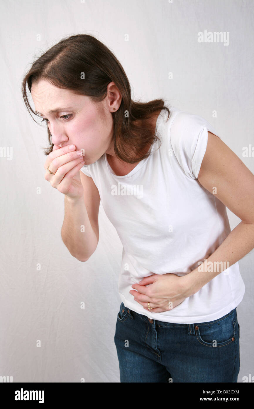 Young woman holds stomach and covers mouth while retching before ...