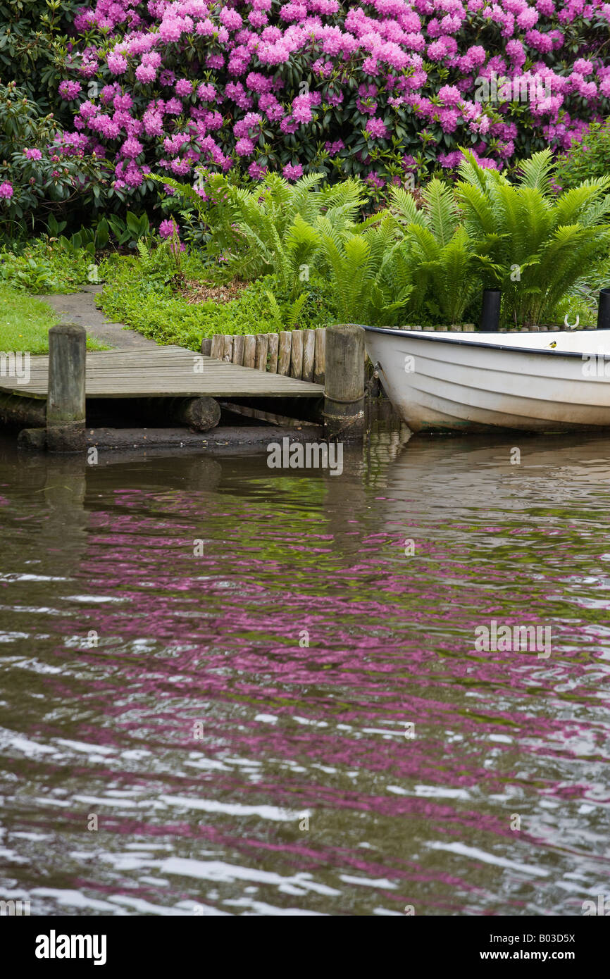 Spring Dock Reflection A small white row boat tied up to a dock that is ...
