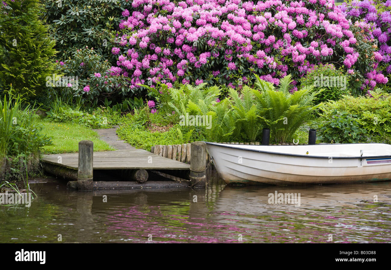 Spring Dock A small row boat tied up to a dock that is surrounded by ...