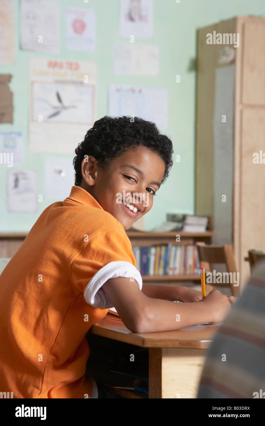 Mixed Race boy writing in classroom Stock Photo - Alamy