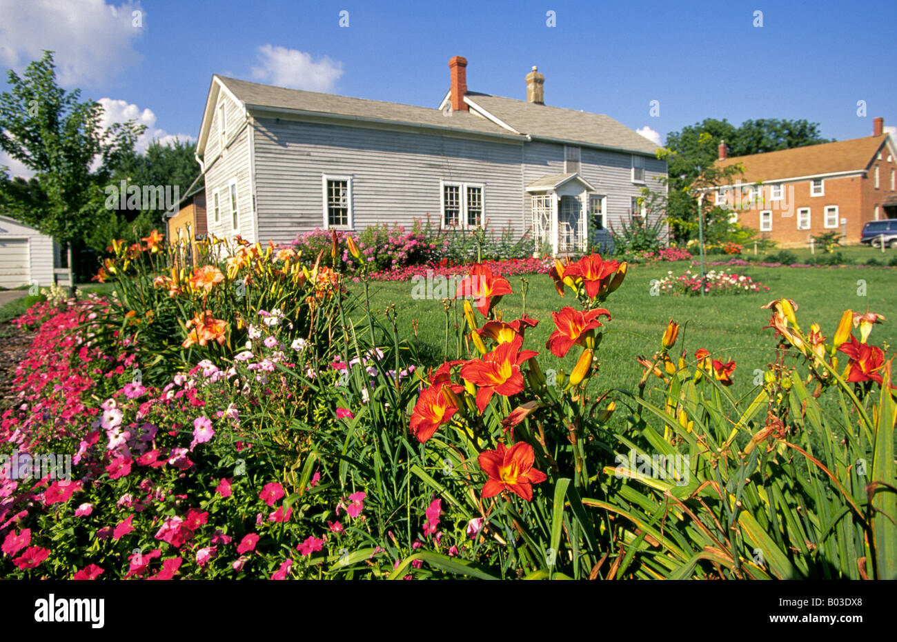 Bright flowers in a garden set off a beautiful but old residential home ...