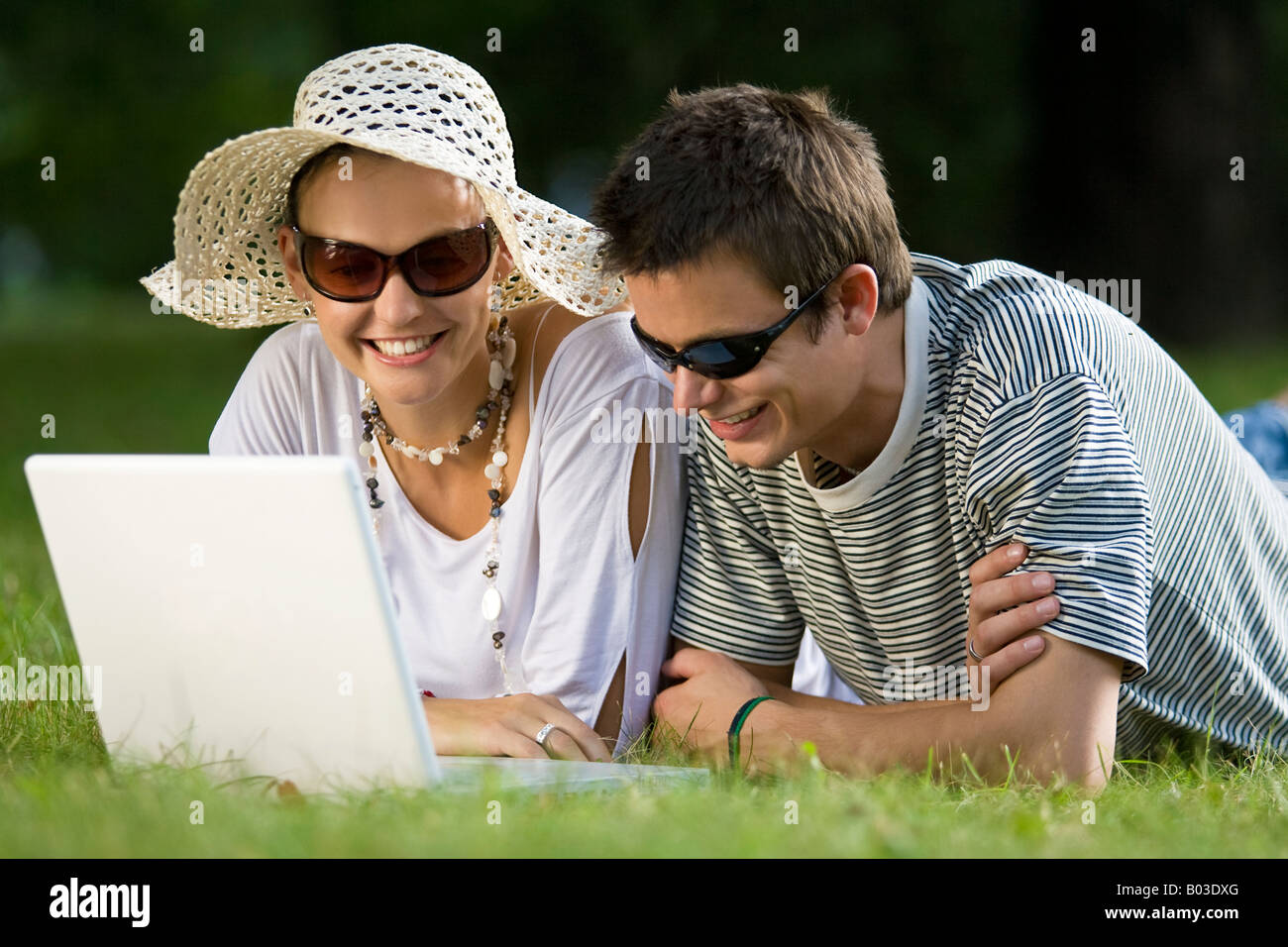 A modern young couple outside in a woodland glade having fun using a ...