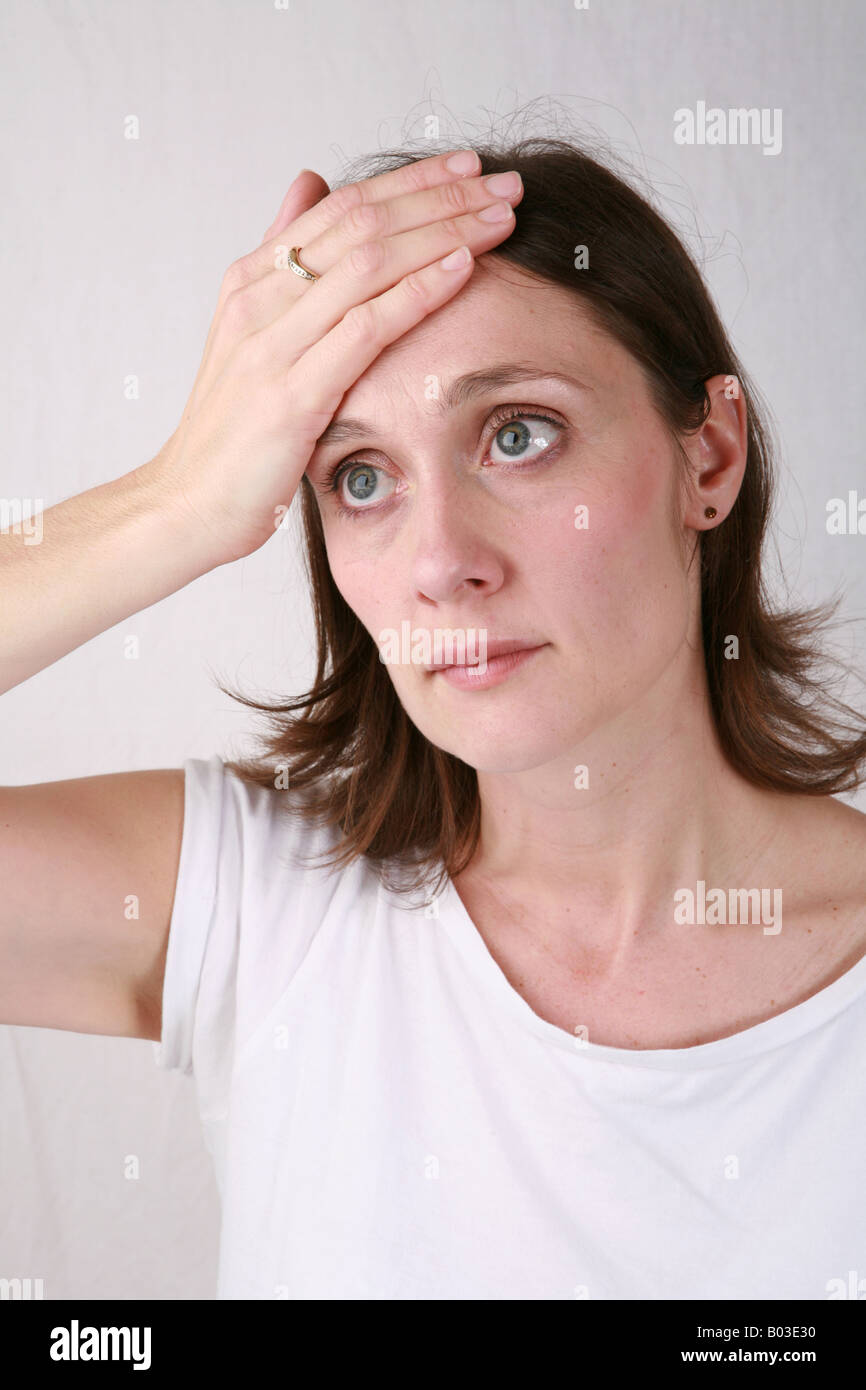 Young woman holds hand on forehead checking for a fever high ...