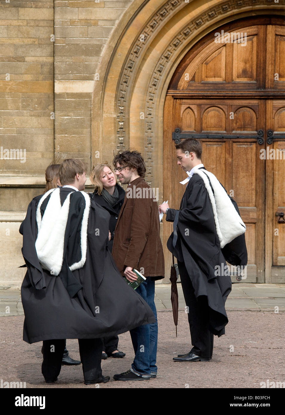 Two new graduates in discussion with friends after the degree ceremony ...