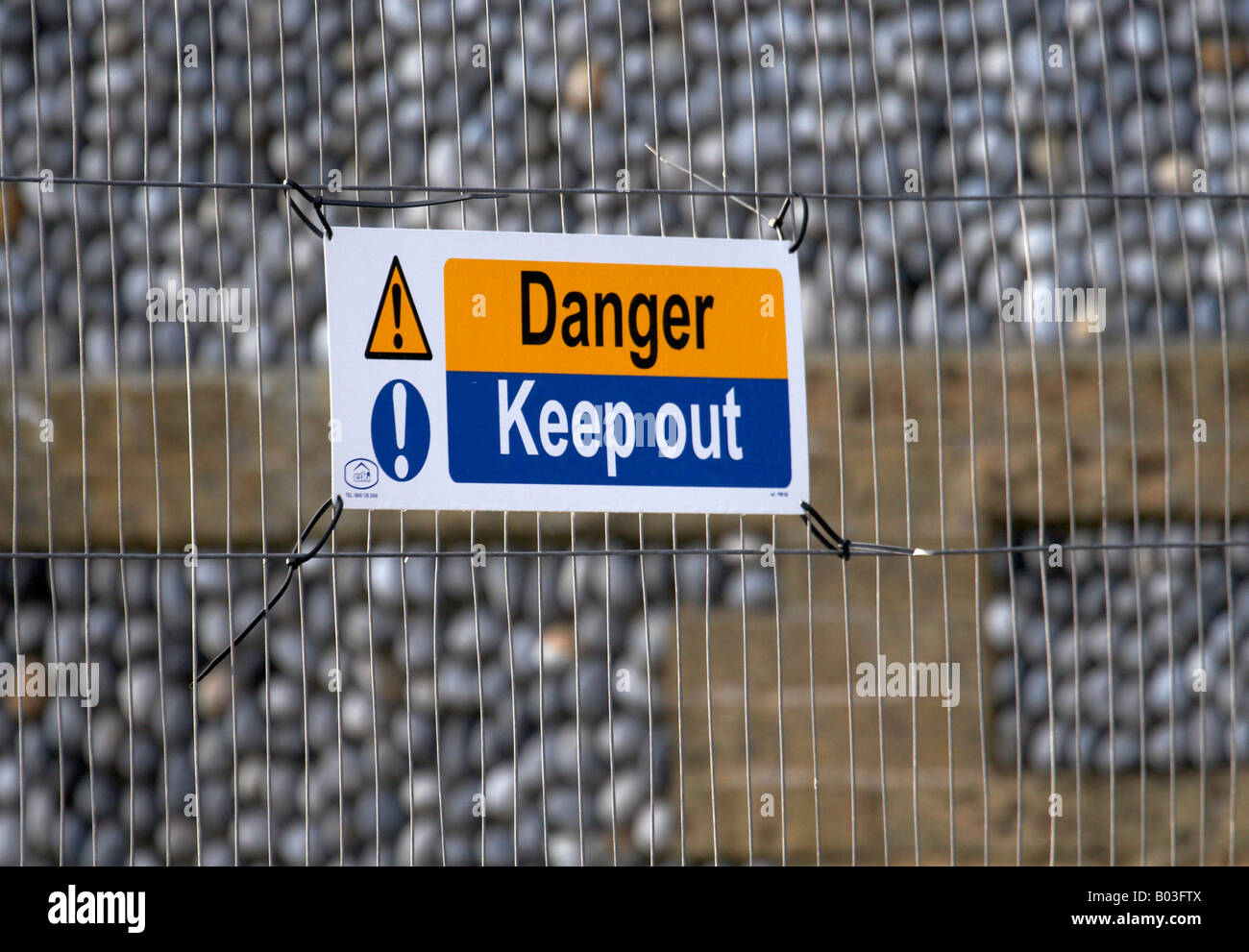 Danger Keep Out Blue & Yellow Sign on a fenced building site with Flint ...