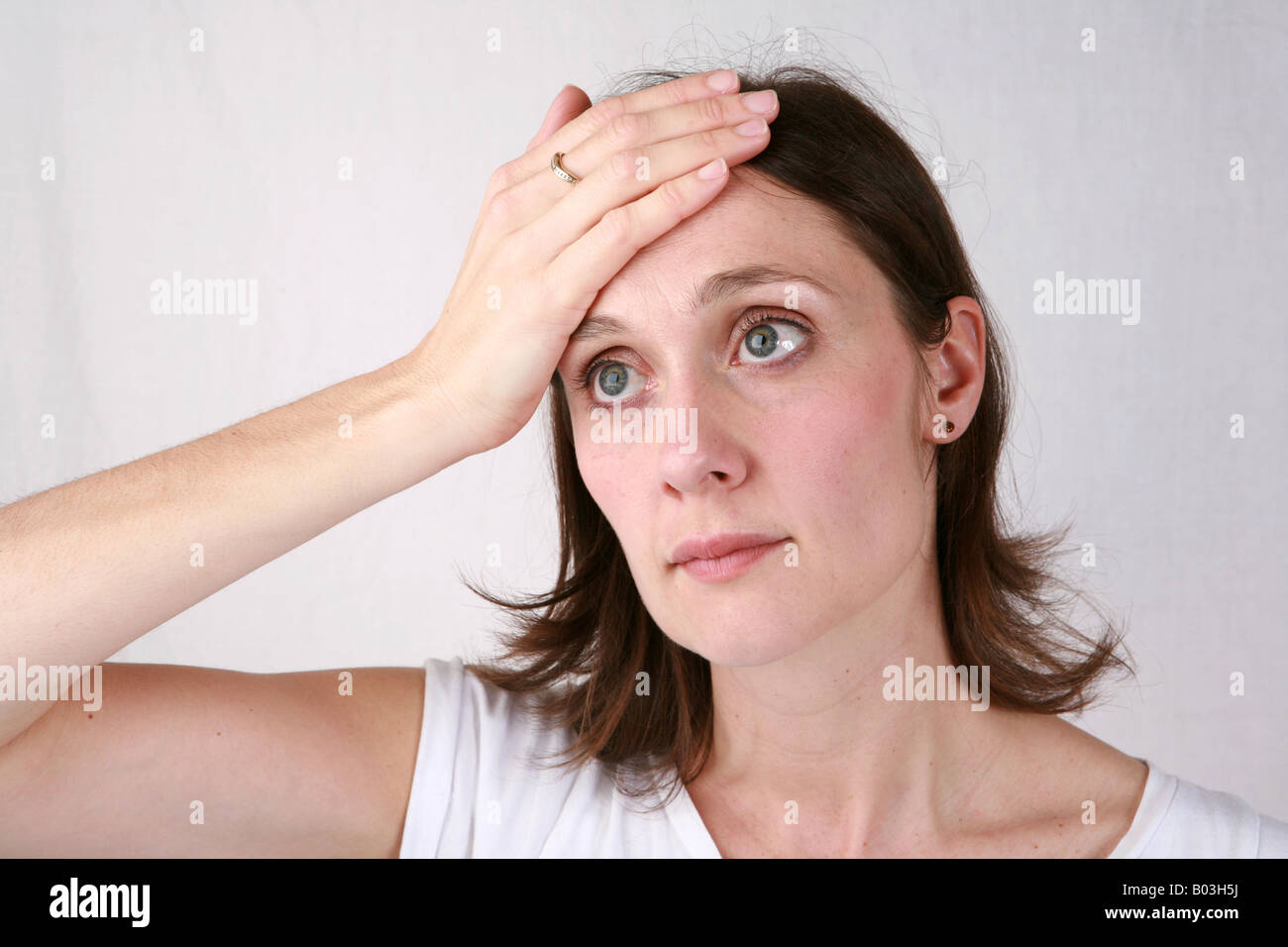 Young woman holds hand on forehead checking for a fever high ...