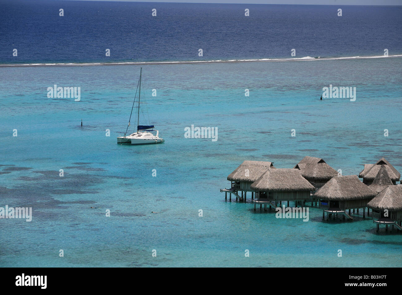 Beach huts along a pontoon within the lagoon around Moorea island in ...