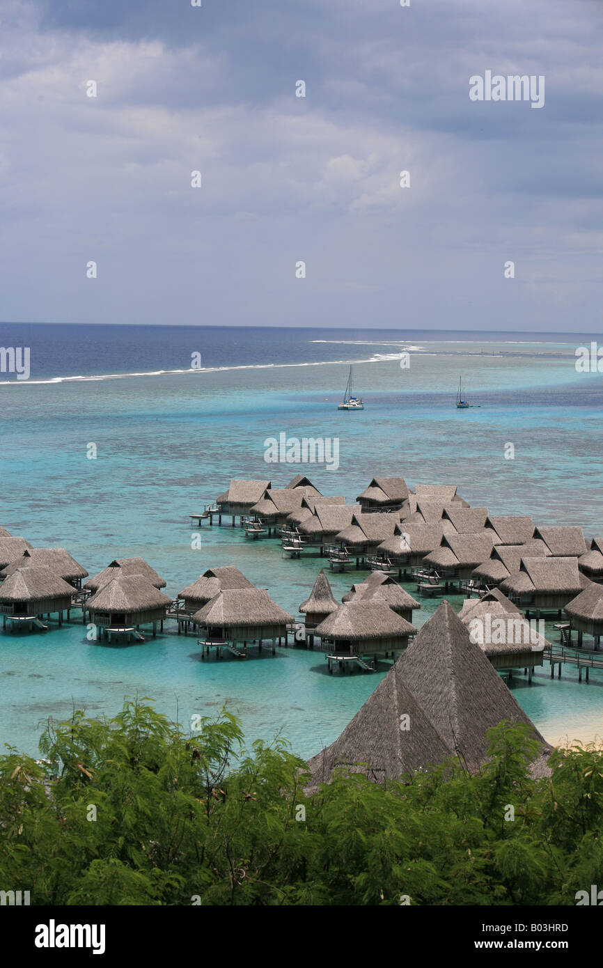 Beach huts along a pontoon within the lagoon around Moorea island in ...