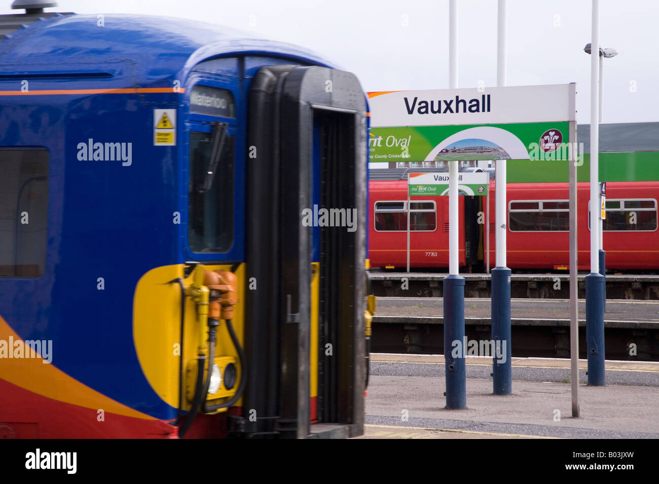 Station platform notice board and passing train at Vauxhall station ...