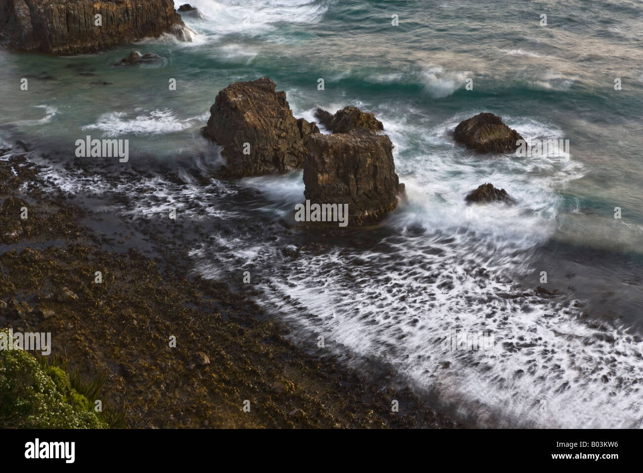 Outcrop of rocks with oncoming waves in the South Island of New Zealand ...