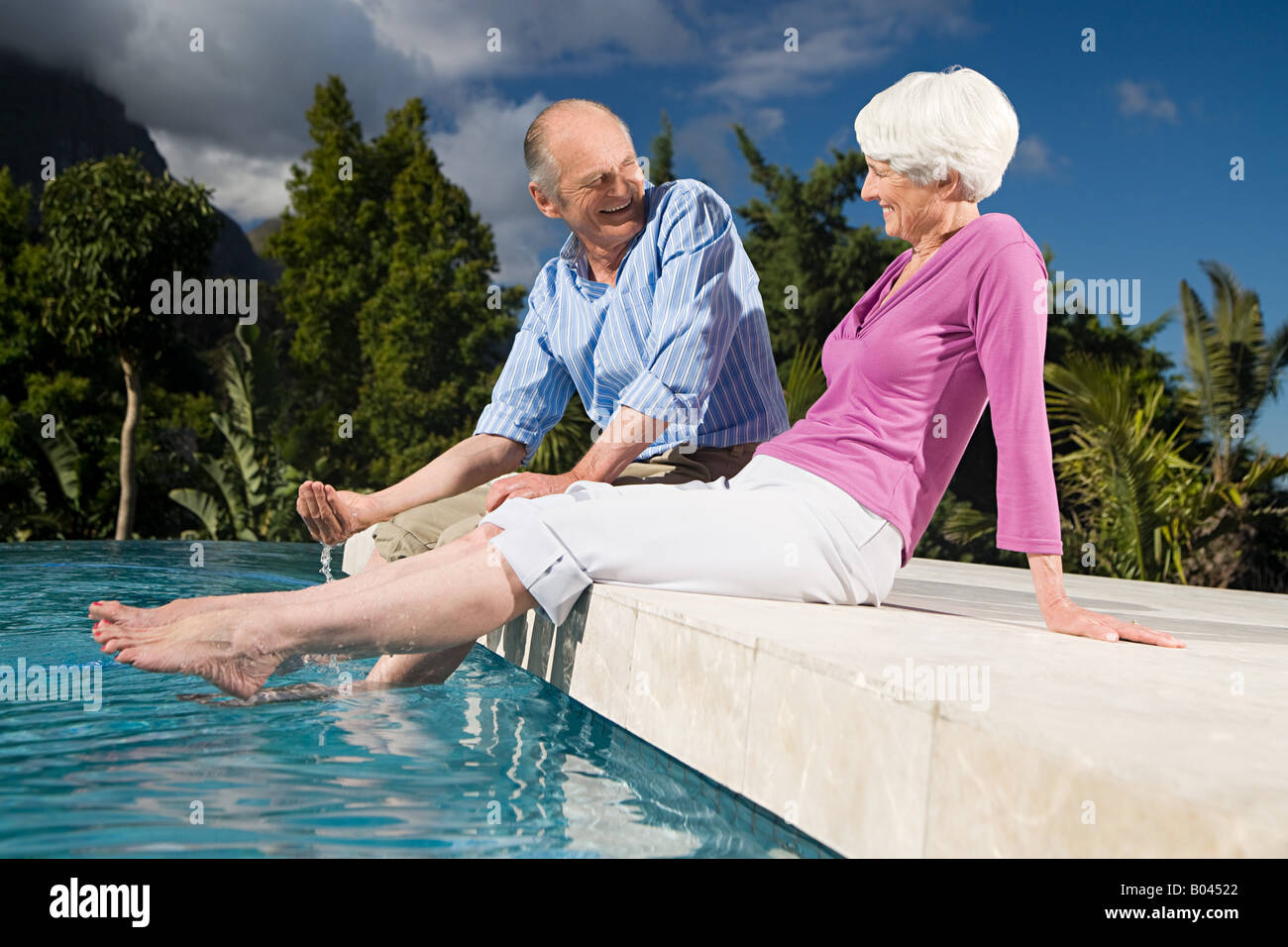 A couple sat next to a pool Stock Photo - Alamy