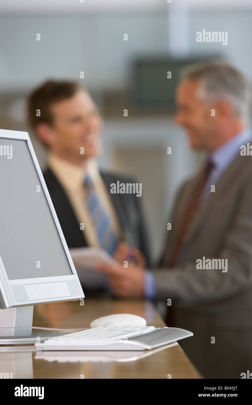 Computer with businessmen in background Stock Photo - Alamy