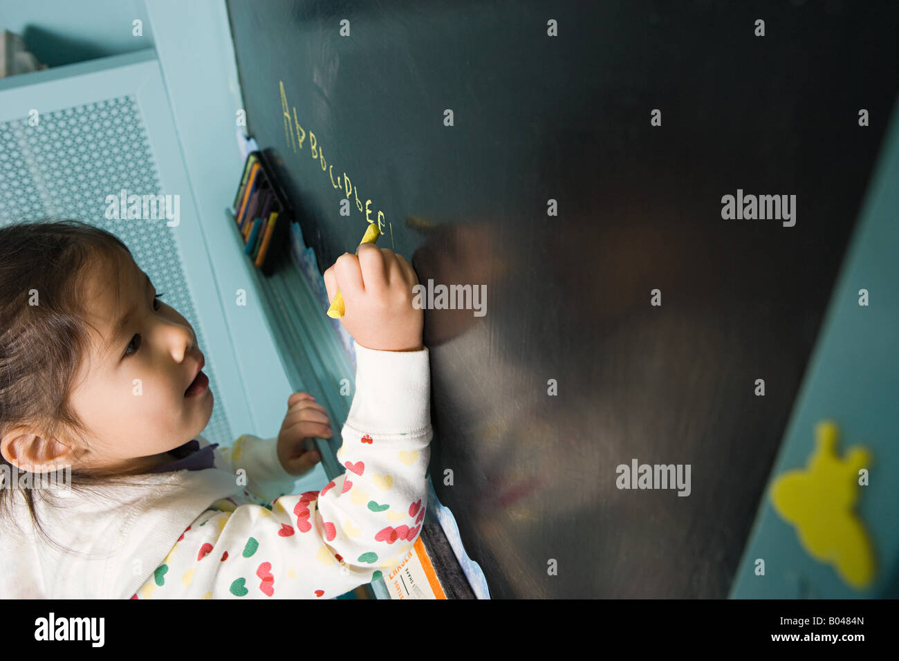 Girl writing on a blackboard Stock Photo - Alamy