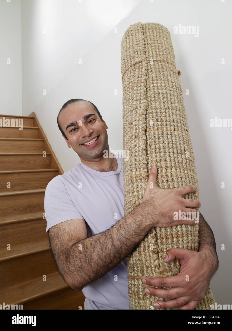 A man holding a rug in his new home Stock Photo - Alamy