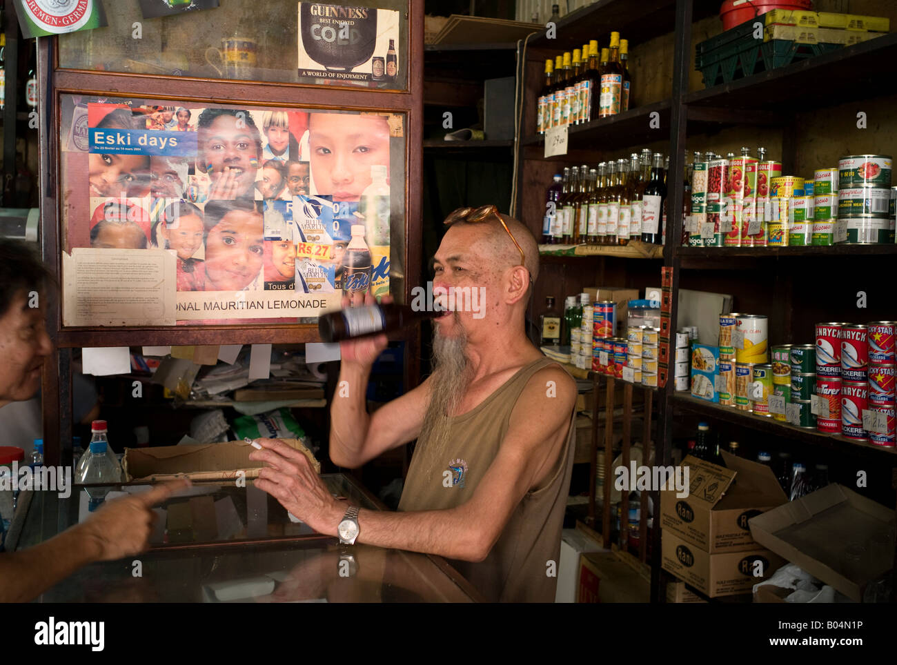 Bearded Chinaman shopkeeper drinking beer from bottle, Port Louis ...