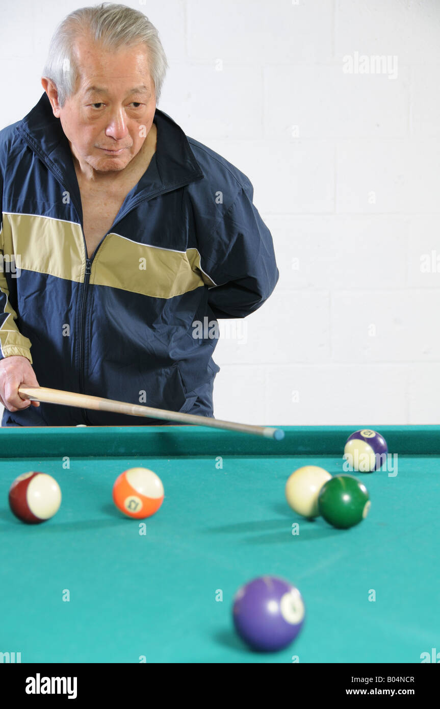 senior asian man playing a game of eight ball one handed Stock Photo ...