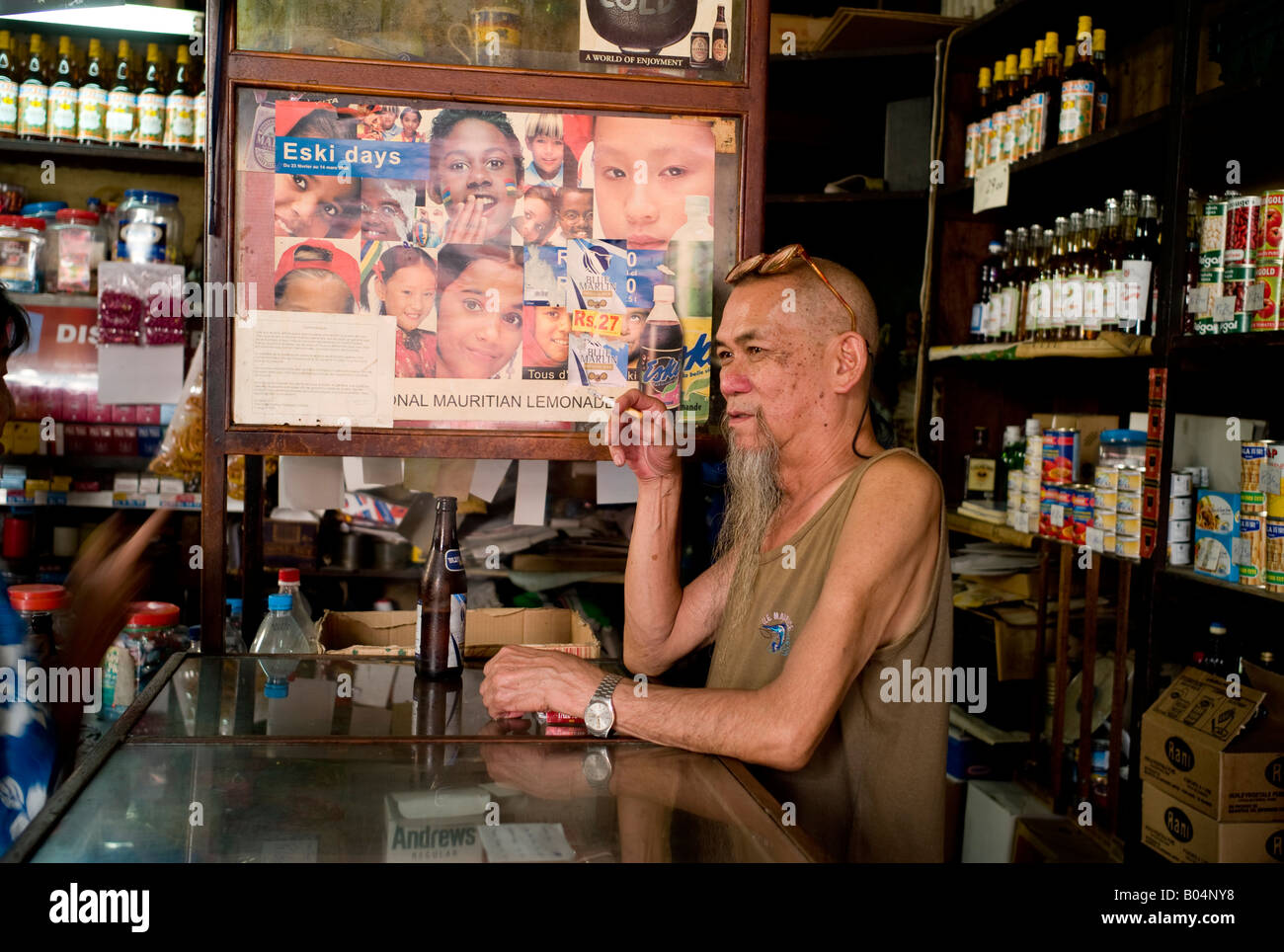 A bearded Chinaman smoking in his shop in Port Louis market, Mauritius ...