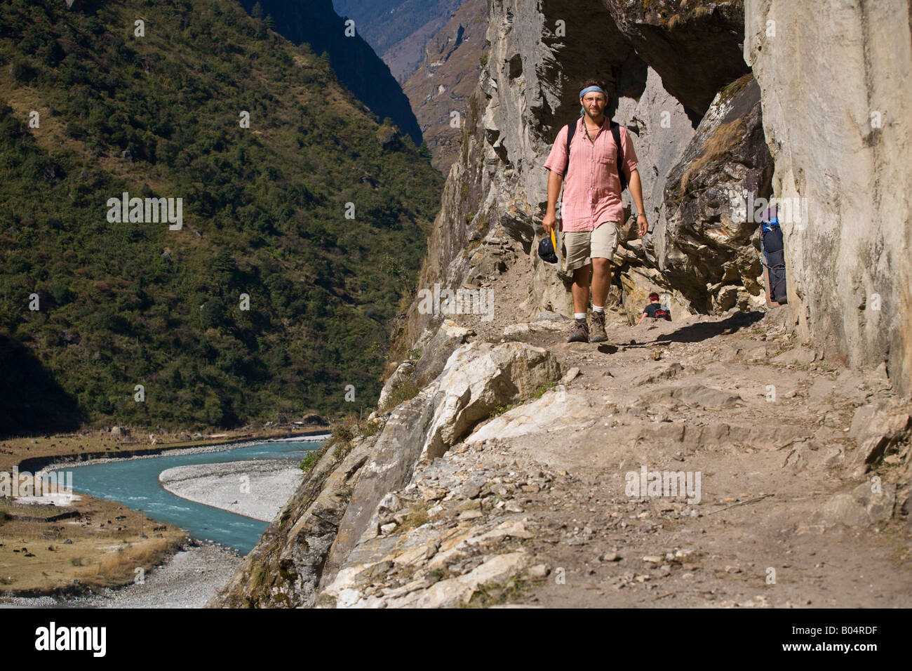A TREKKER walks along a HIKING TRAIL hewn from a cliff face above the ...
