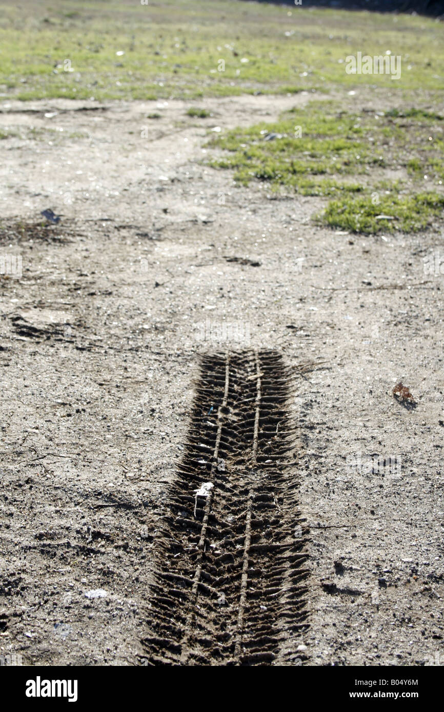 one single car tyre track in mud in field on derelict ground in ...