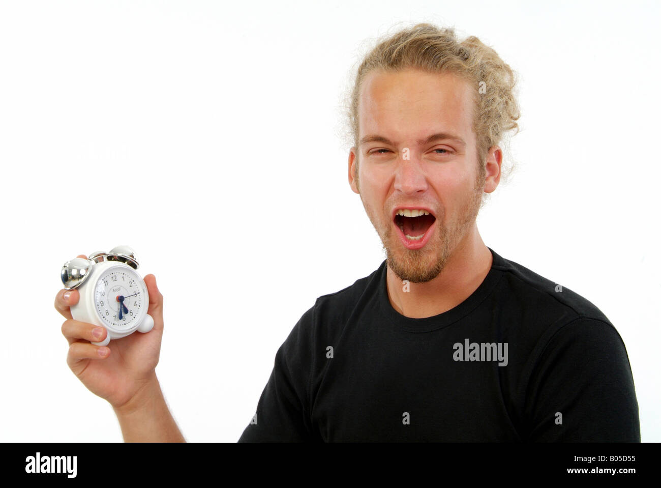 sleep-deprived young man with alarmclock in hand Stock Photo - Alamy
