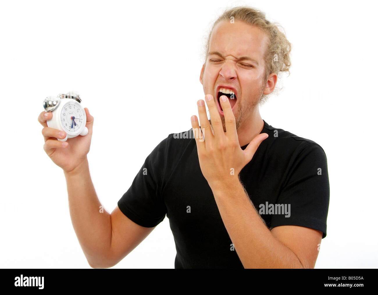 sleep-deprived young man with alarmclock in hand Stock Photo - Alamy