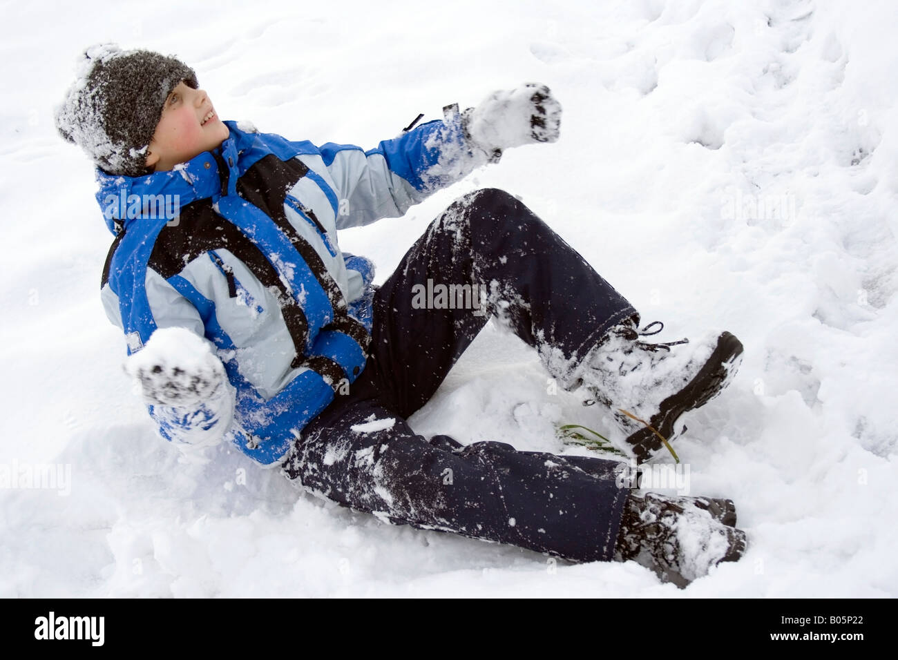 Boy having fun and rolling in the snow Stock Photo - Alamy