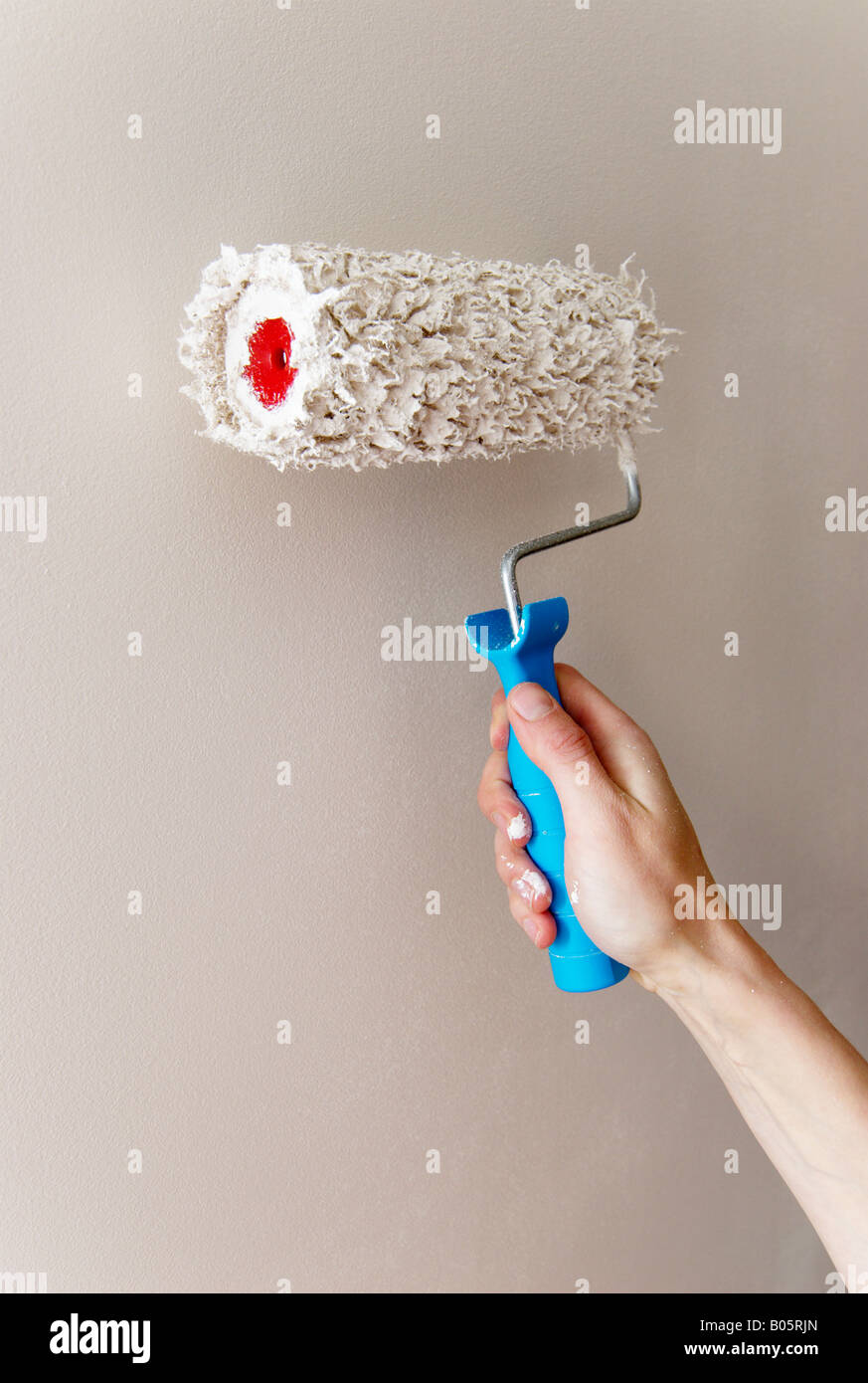 Hand and paint-roller. Painting a wall white Stock Photo - Alamy
