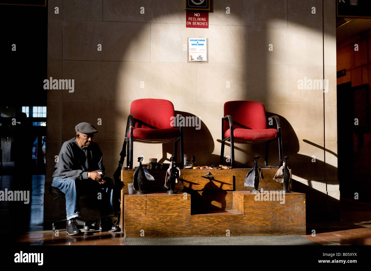 A shoe shine vendor waits for customers as early morning light shines ...