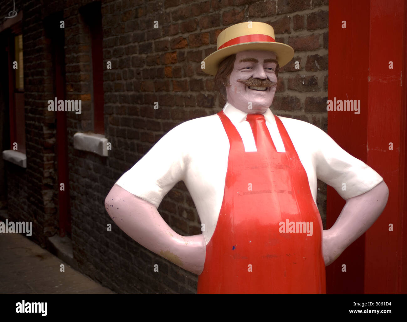 Red Model Butcher against brick wall with a hat Stock Photo - Alamy