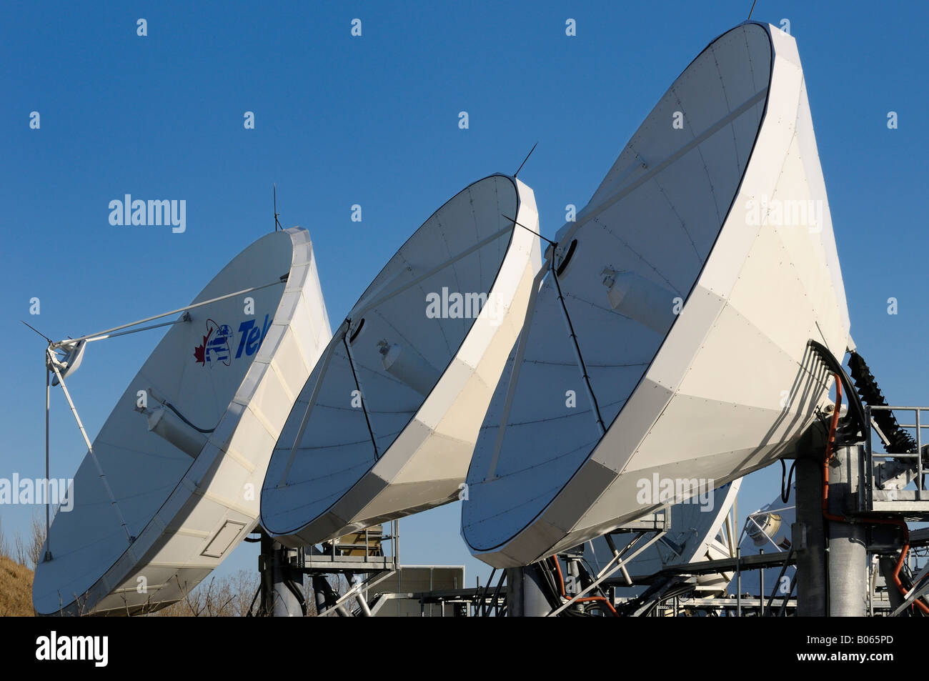 Three large satellite communication dish receivers against a clear sky ...