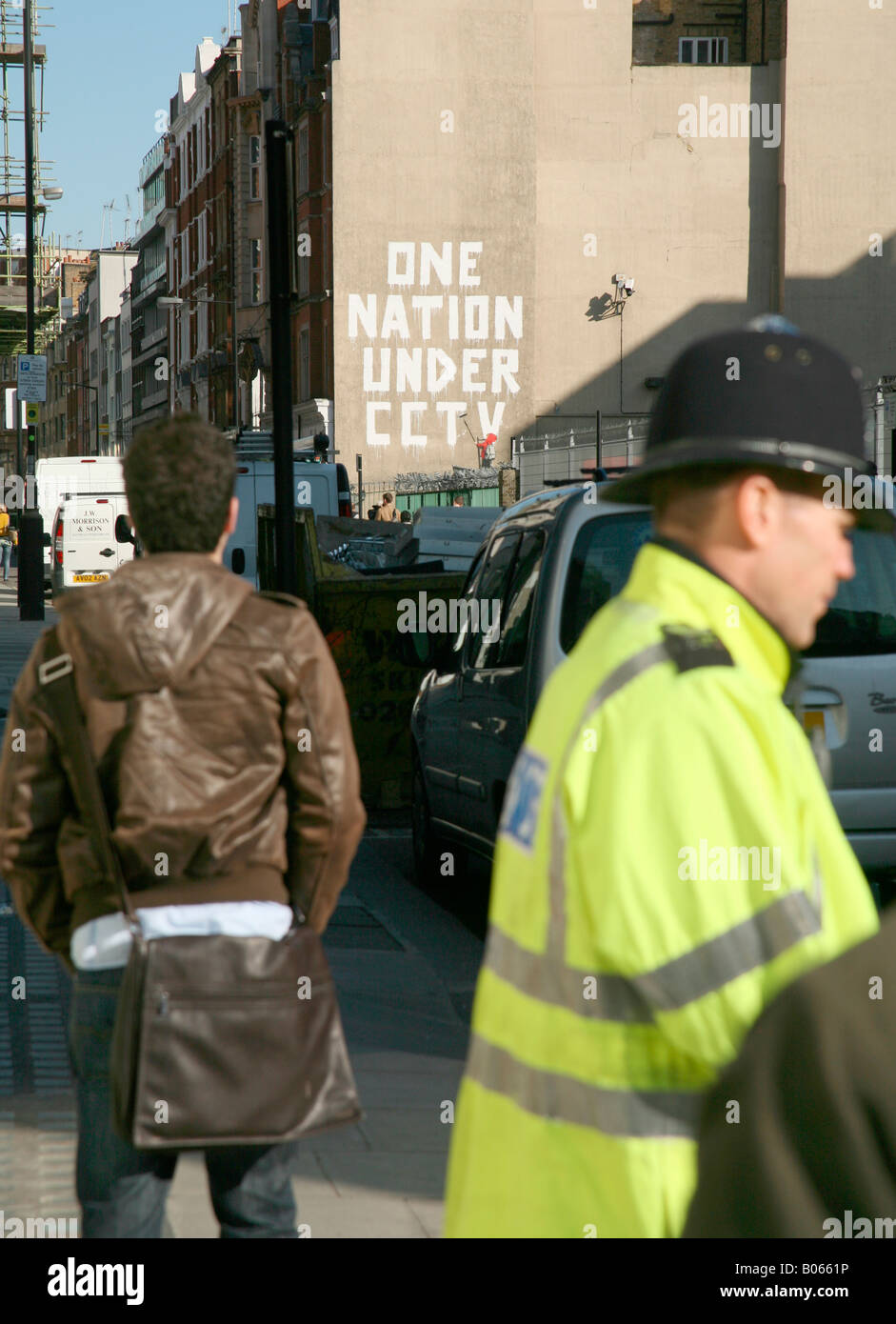 Police officer stood in front of Banksy CCTV graffiti, London Stock ...