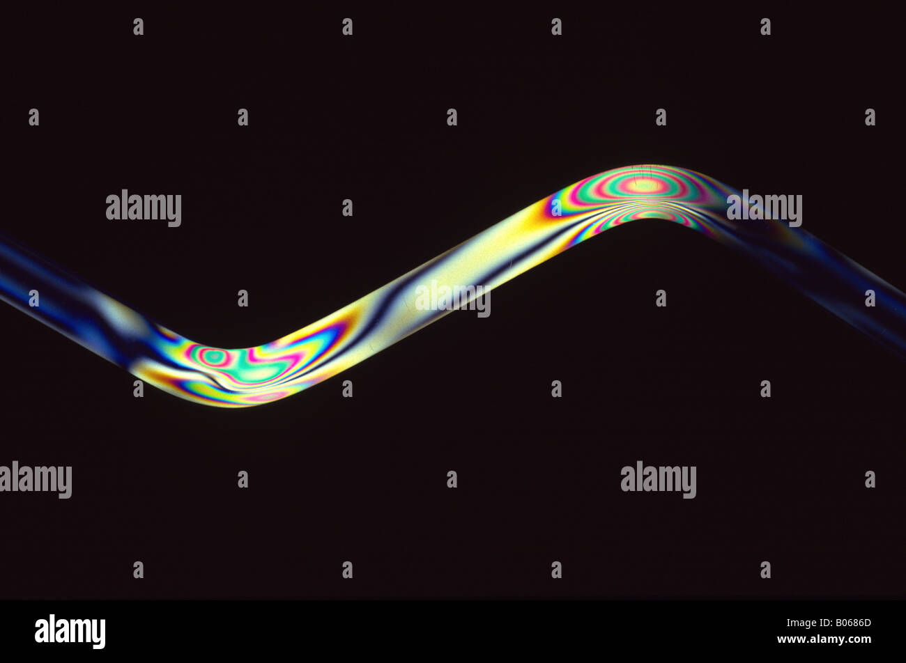 Close up of stress patterns in bent plastic rod. Cross polarized ...